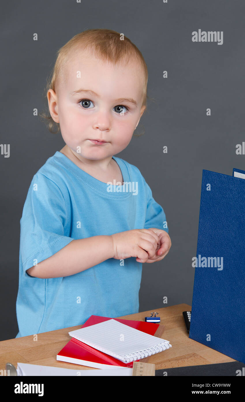 young child at small desk in grey background Stock Photo - Alamy