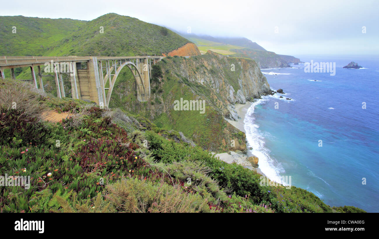 View of concrete arch bridge over gorge with mountains on one side and ...