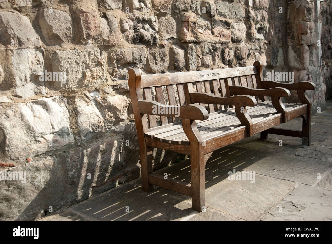 Bench with stone wall background Stock Photo - Alamy