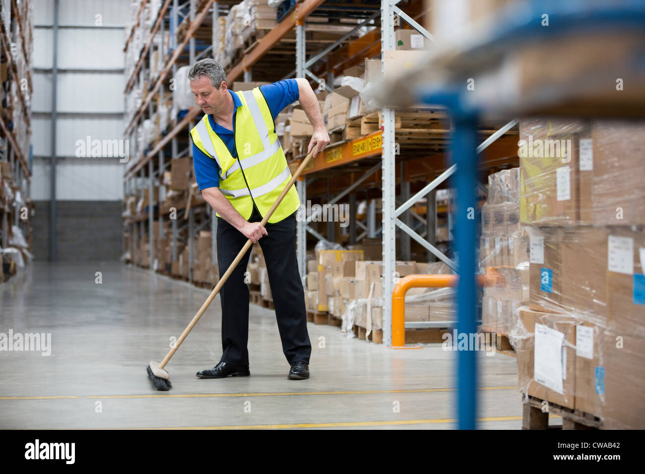 Man sweeping warehouse floor with broom Stock Photo - Alamy