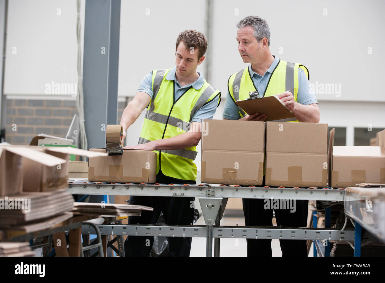 Men packing cardboard box in warehouse Stock Photo - Alamy