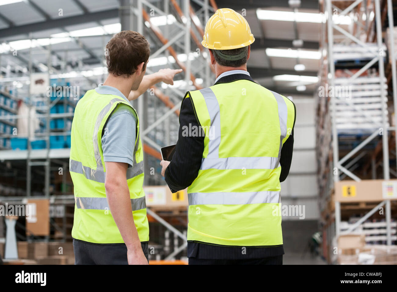 Two men in warehouse, one pointing Stock Photo - Alamy