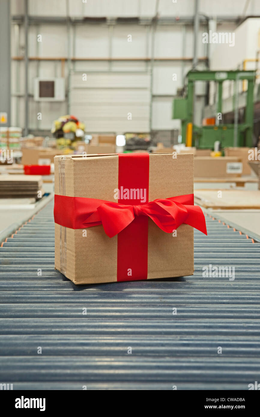 Cardboard box with red bow on conveyor belt Stock Photo - Alamy