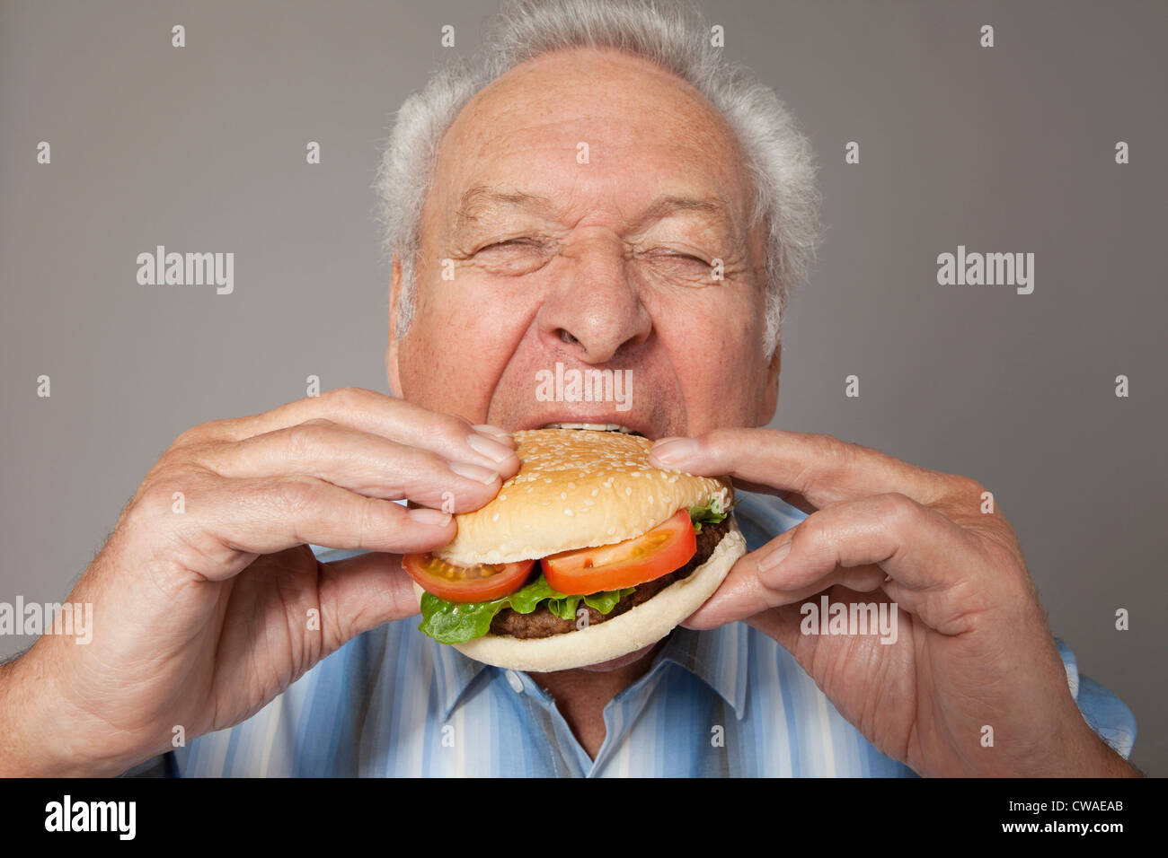 Senior man eating burger Stock Photo - Alamy