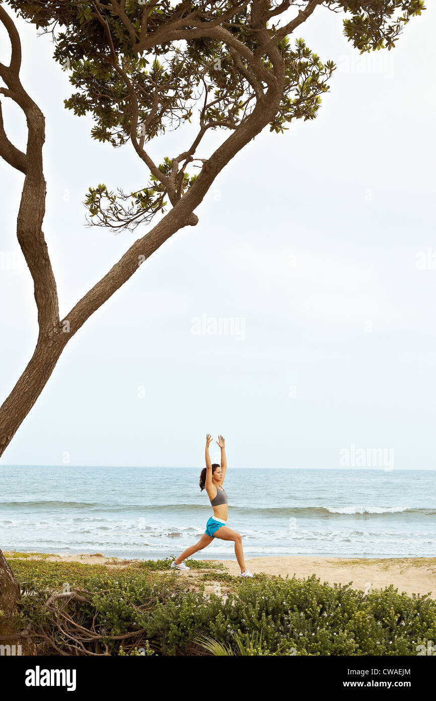 Young woman stretching on beach Stock Photo - Alamy