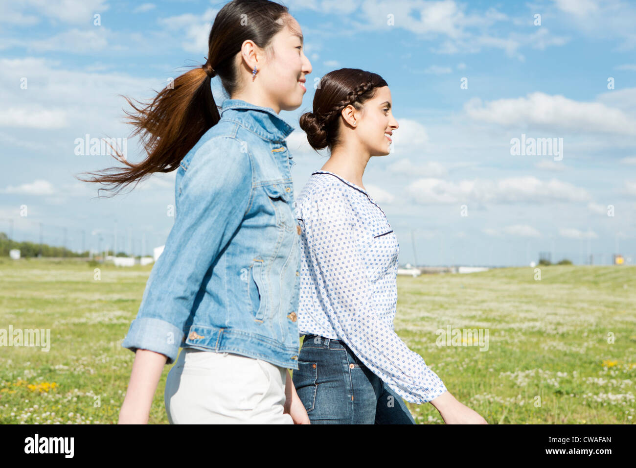 Two young women walking in field Stock Photo - Alamy
