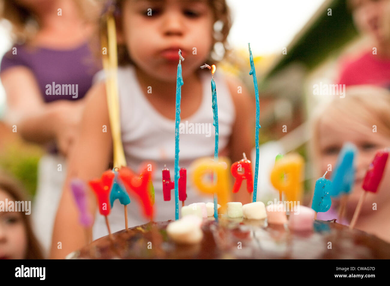 3 year old girl blowing out candles on birthday cake Stock Photo - Alamy