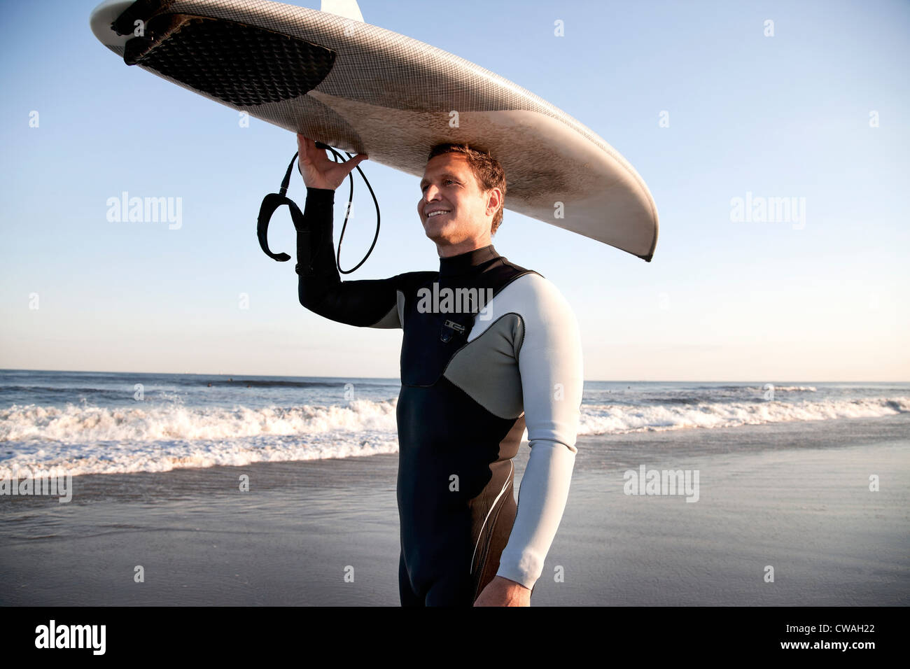Surfer carrying surfboard on head Stock Photo - Alamy
