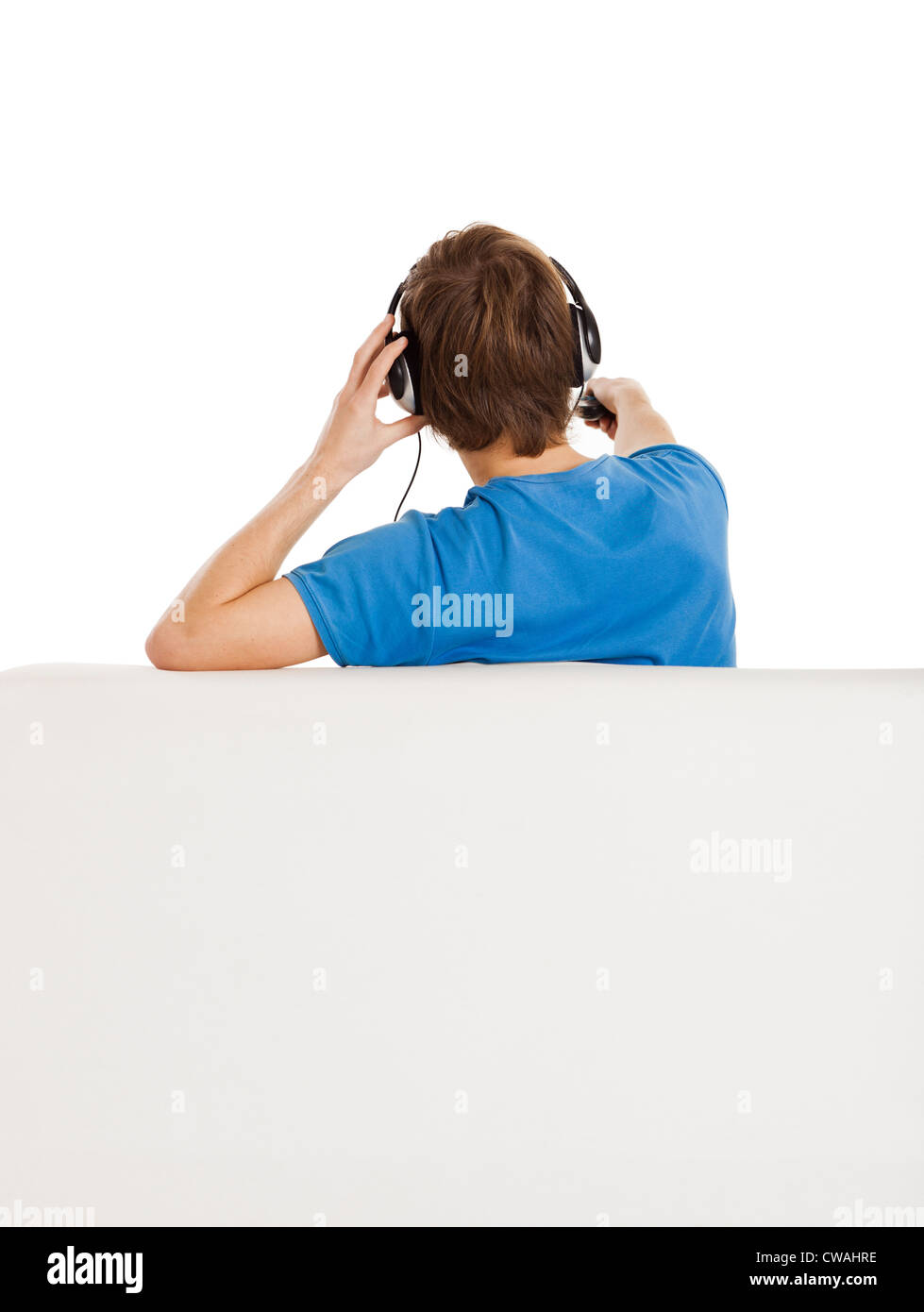 Young man sitting on the couch using a remote control, with copyspace ...