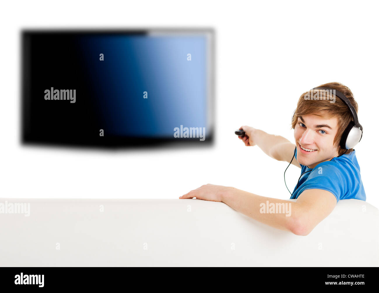 Young man sitting on the couch using a remote control and watching tv ...