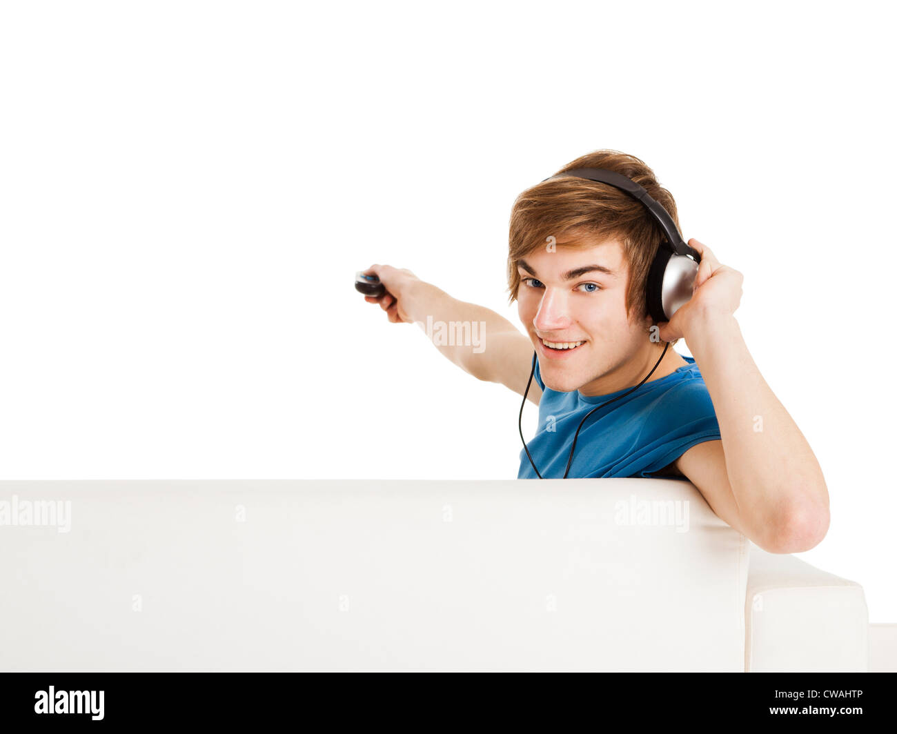 Young man sitting on the couch using a remote control, with copyspace ...