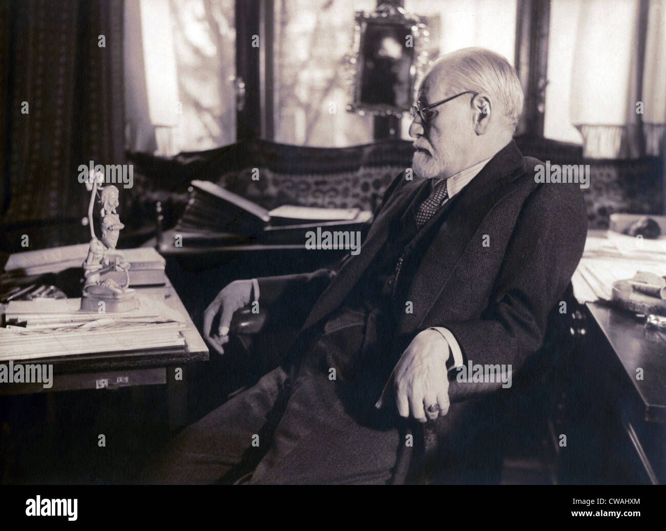 Sigmund Freud seated in his study contemplating a carved figurine ...