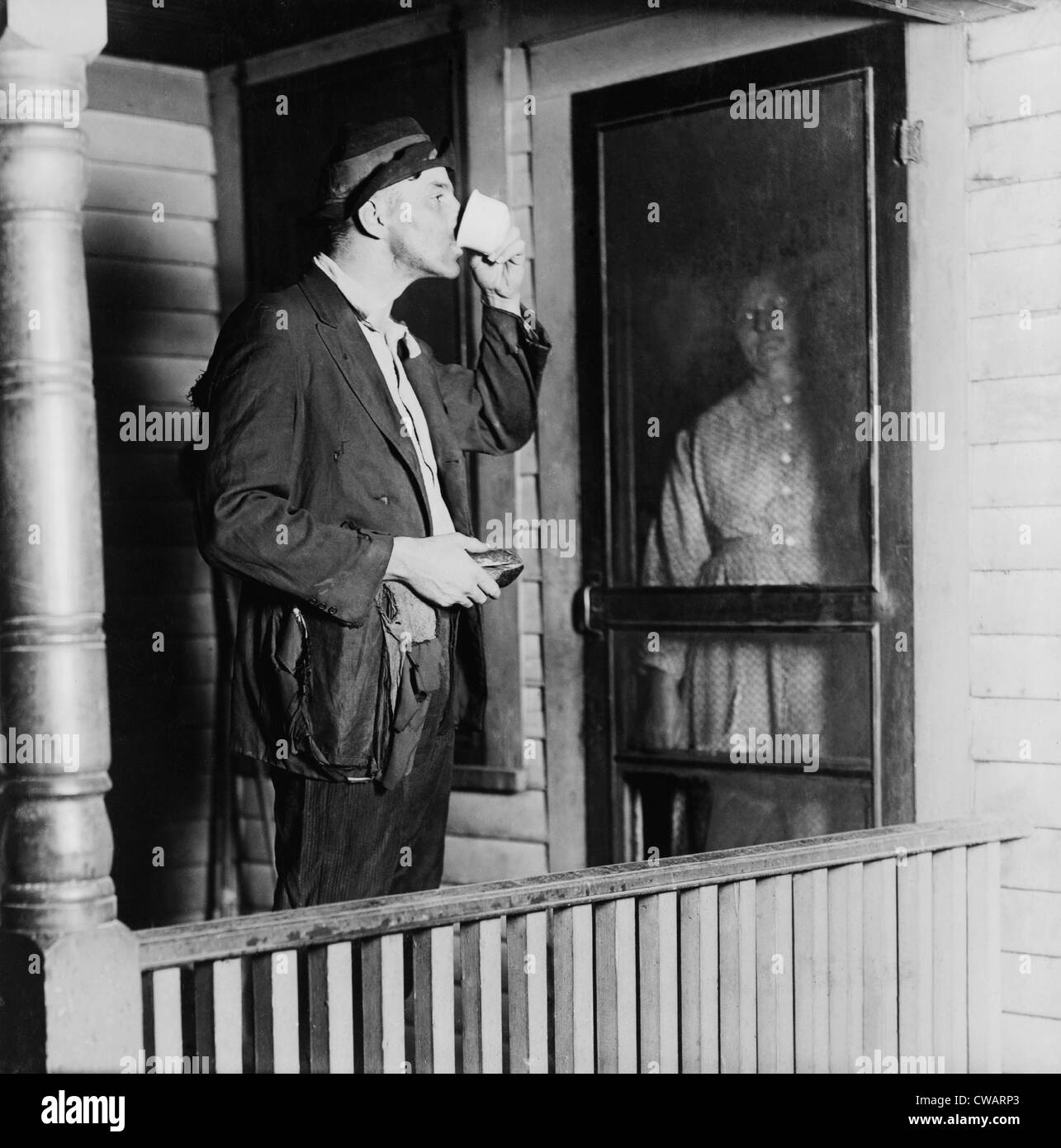 Homeless man in ragged clothes eating a meal standing as his benefactor ...