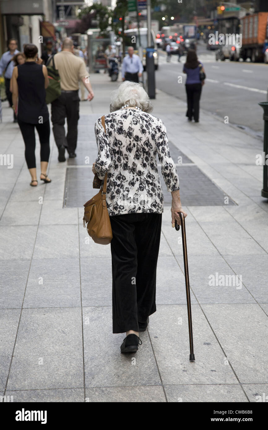 80 something woman with cane walks along 57th Street in Manhattan Stock ...