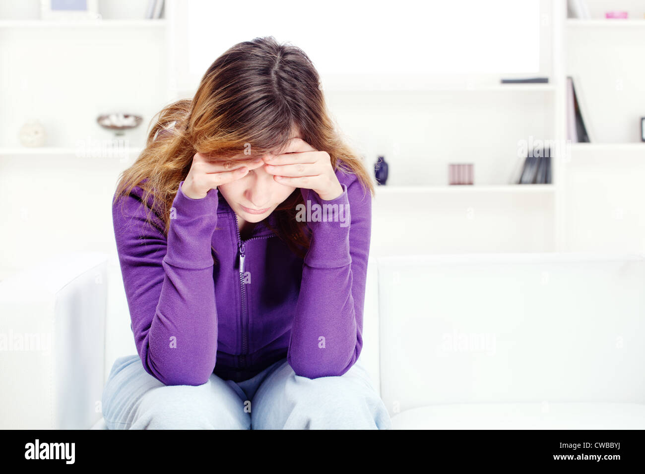 teenager girl at home seating on sofa and covering face with hands ...