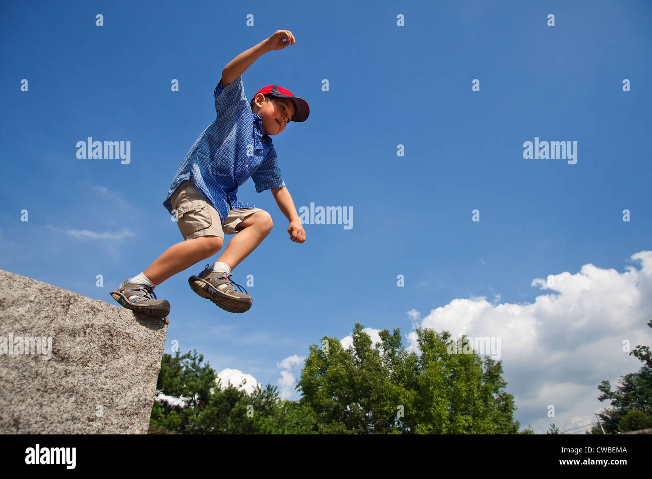 A young boys starts to leap off a rock Stock Photo - Alamy