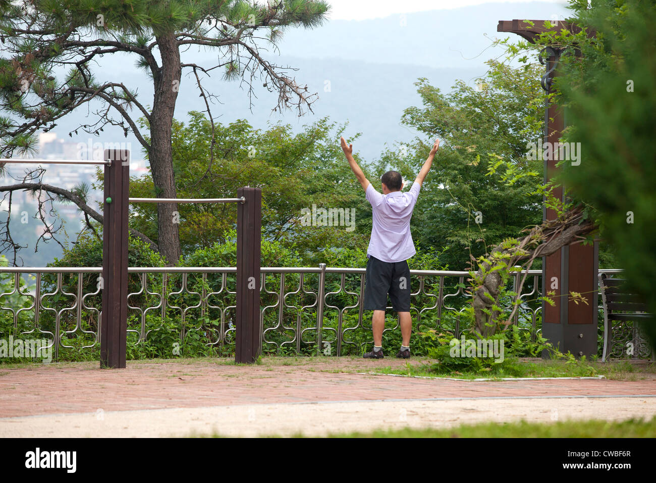 A Korean man stretches during an exercise routine near Seoul, Korea ...