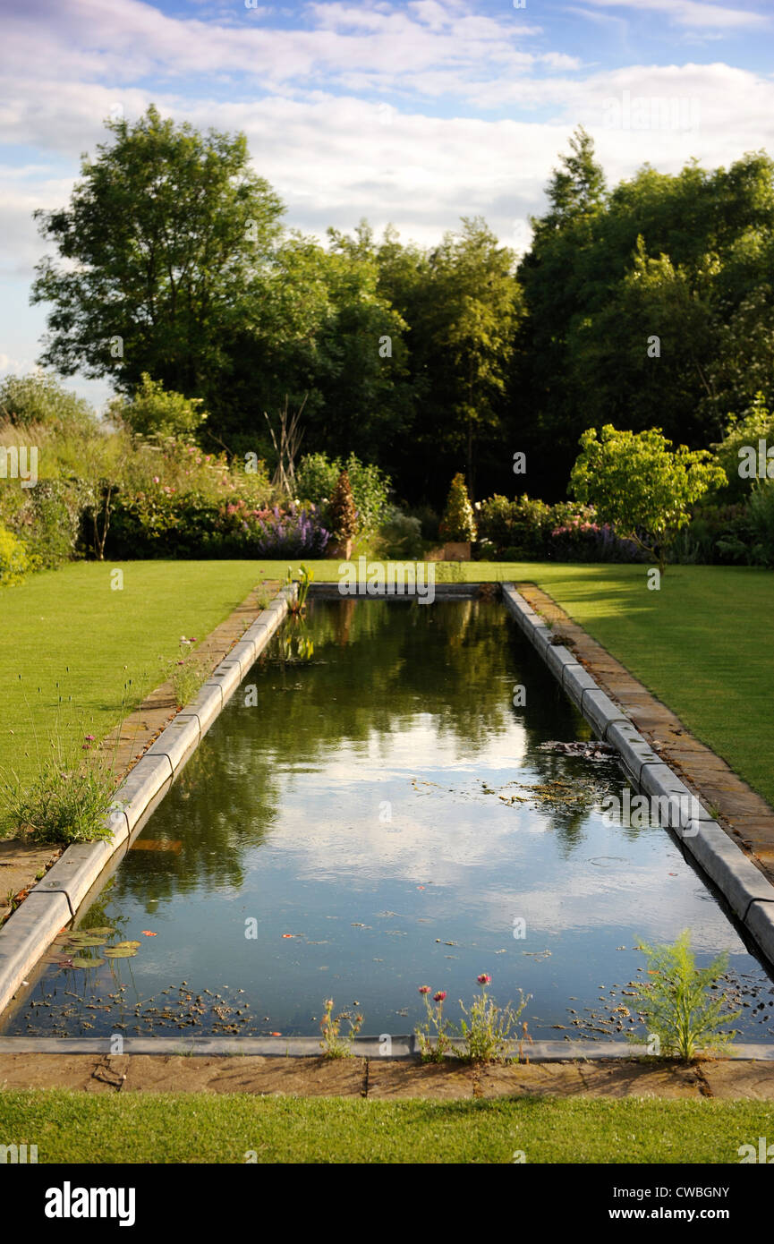 A pond with lawn and herbaceous borders in an English country garden UK ...