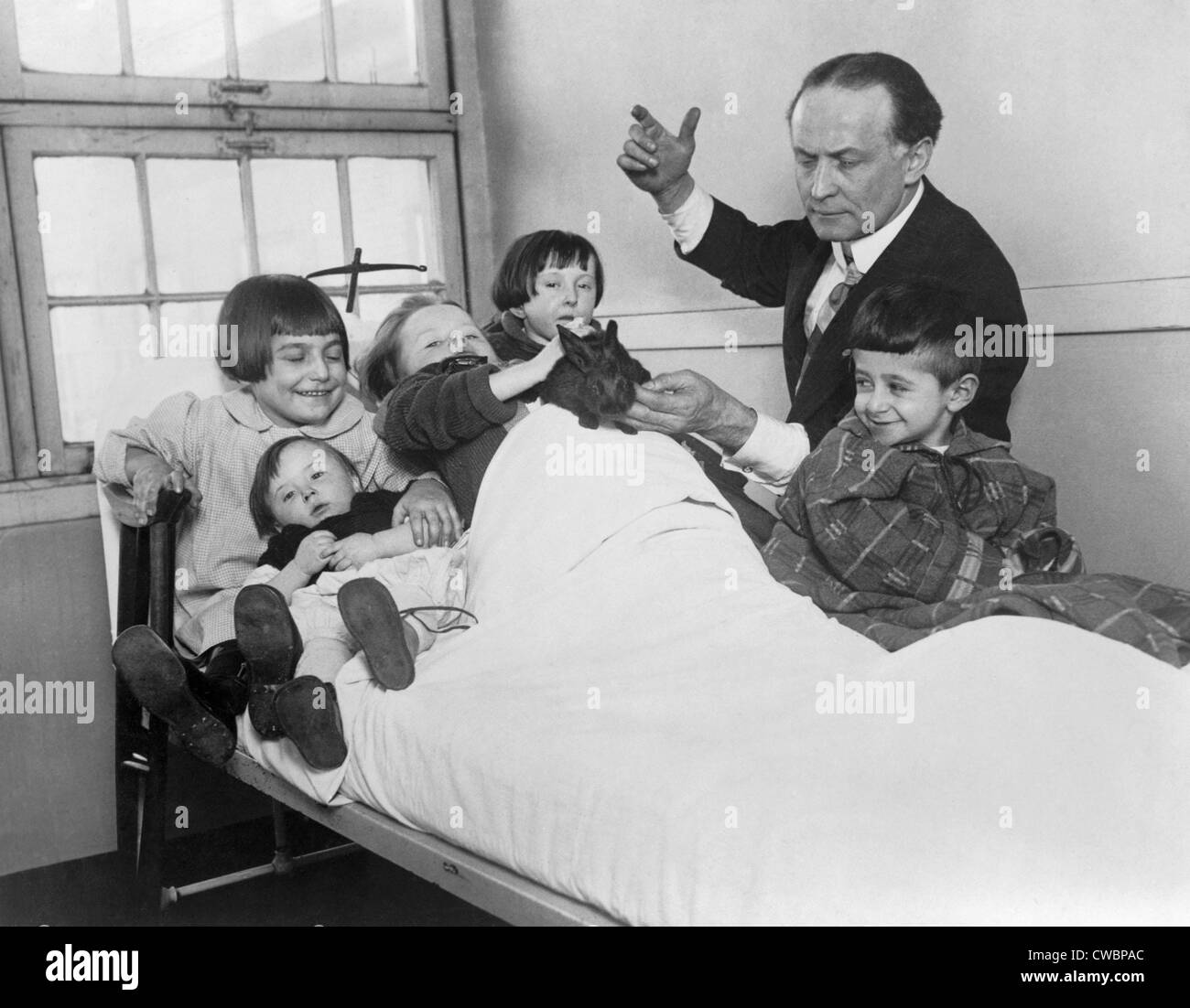 Harry Houdini and his rabbit entertain five hospitalized children. Ca ...