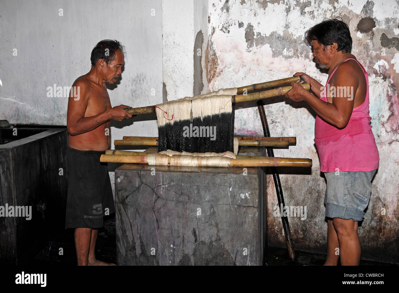 A process of Ikat fabric weaving. The warp thread is dyed a solid color ...