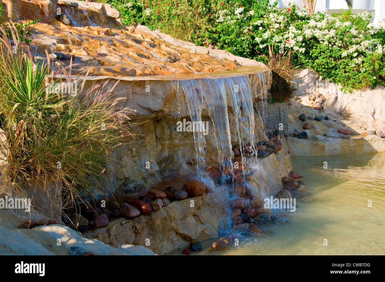 Water flow in an artificial waterfall on warm sunset lighting time ...