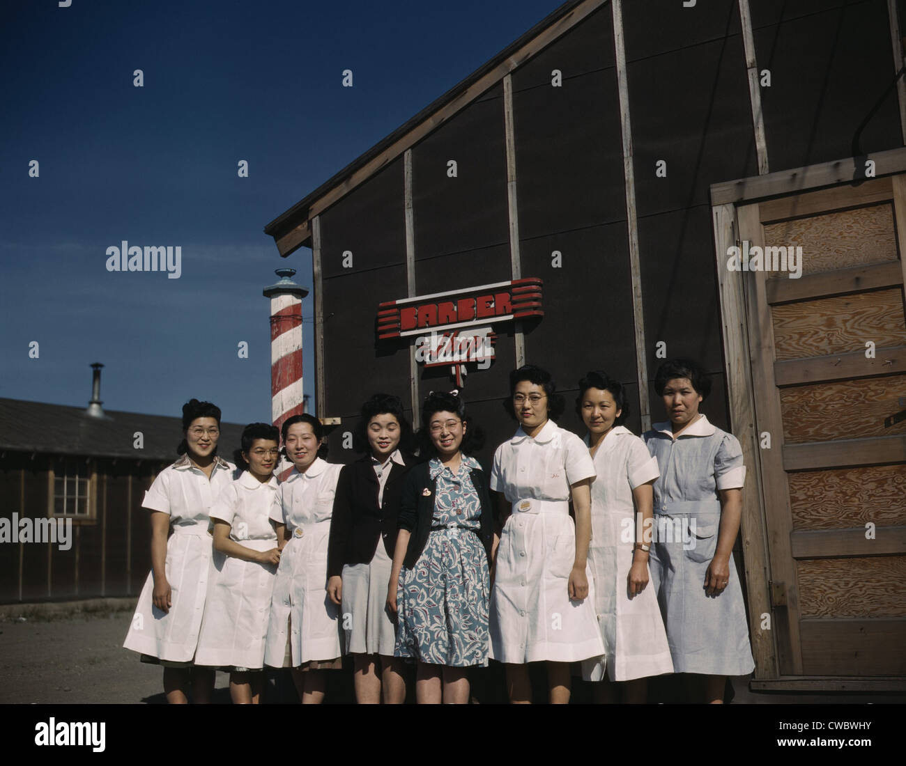 Eight Japanese American women pose for a photograph in front of a camp ...