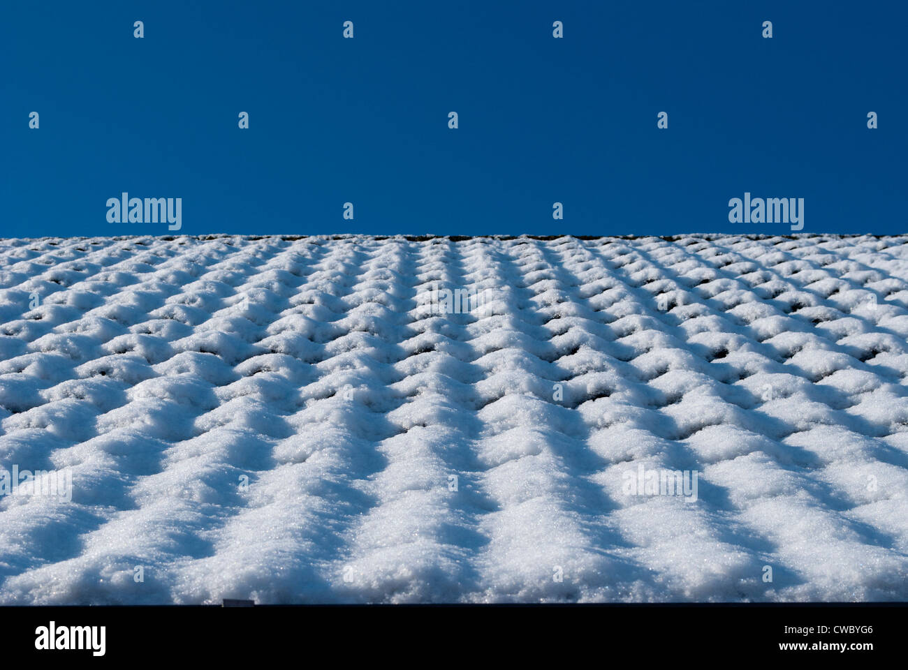 Snow covered tiled roof against a deep blue sky Stock Photo - Alamy