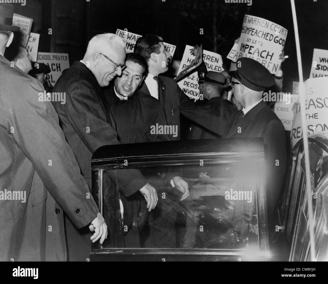 Chief Justice Earl Warren is escorted through crowd of protestors ...