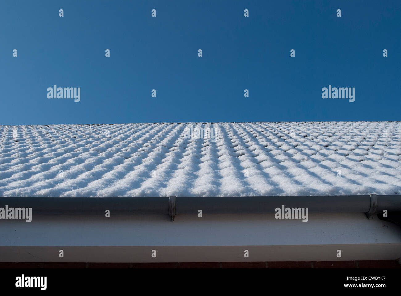 Snow covered tiled roof against a deep blue sky Stock Photo - Alamy