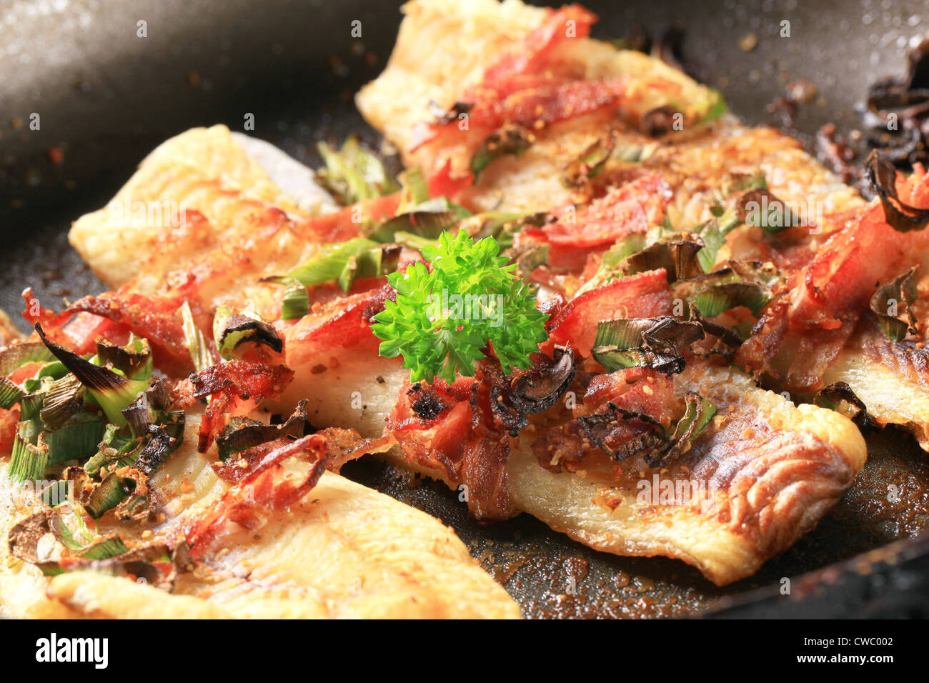Pan fried fish fillets with bacon and spring onion Stock Photo - Alamy