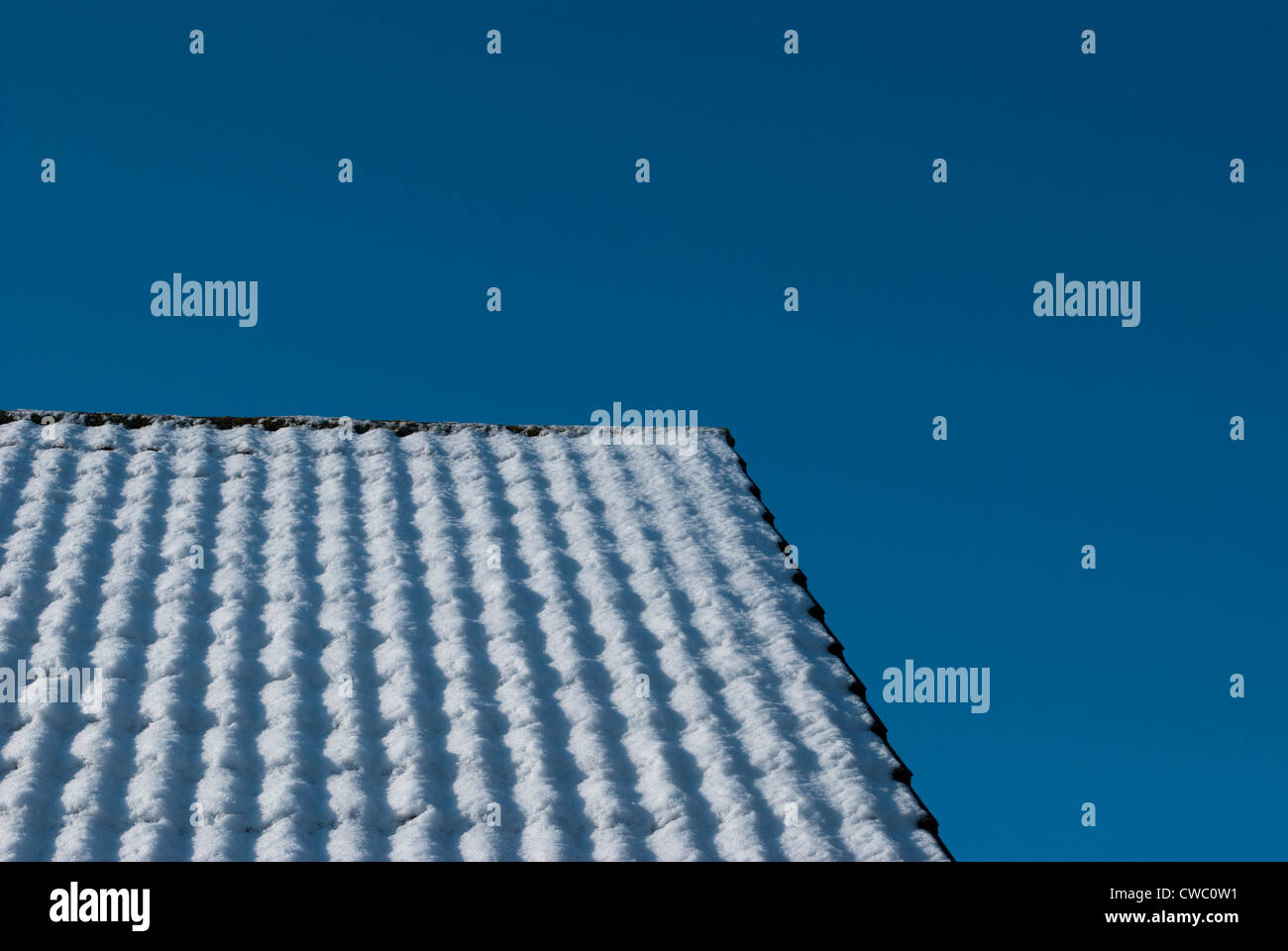 Snow covered tiled roof against a deep blue sky Stock Photo - Alamy