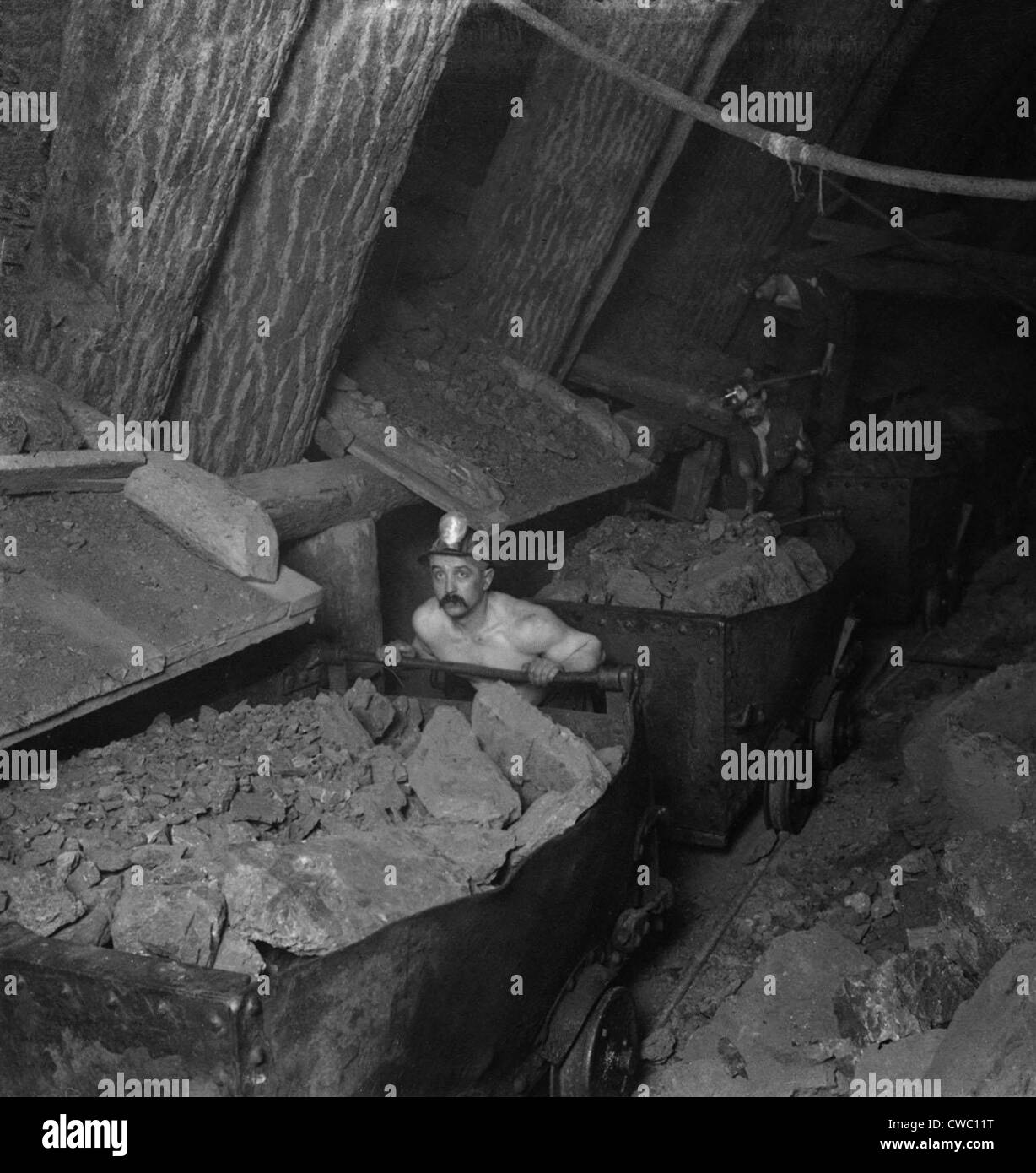 A miner working a mine underground, loading and handling cars with ...