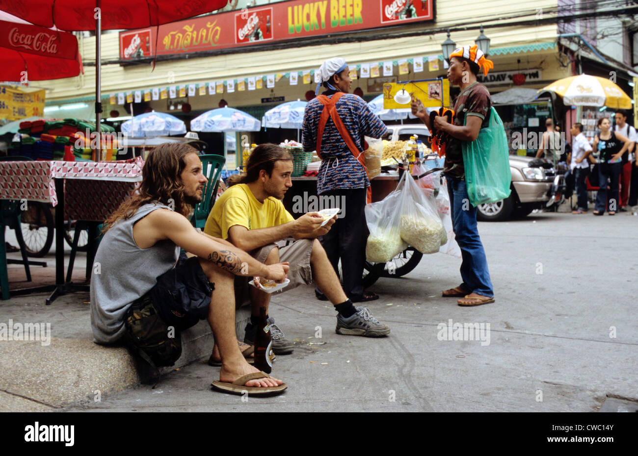 Bangkok, travelers sitting on the roadside eating and look Stock Photo ...