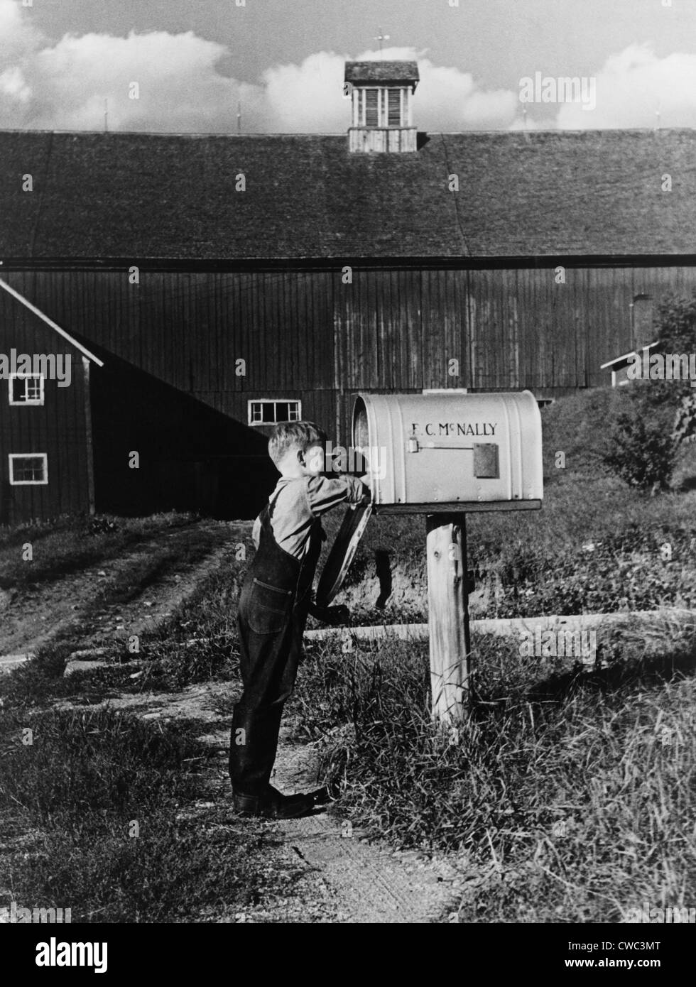 Boy reaching into the mailbox on the McNally farm in Kirby Vermont ...
