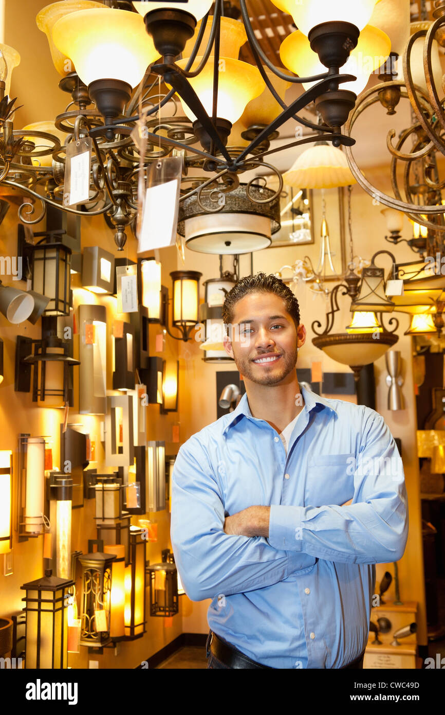 Portrait of happy handsome man standing with arms crossed in store ...