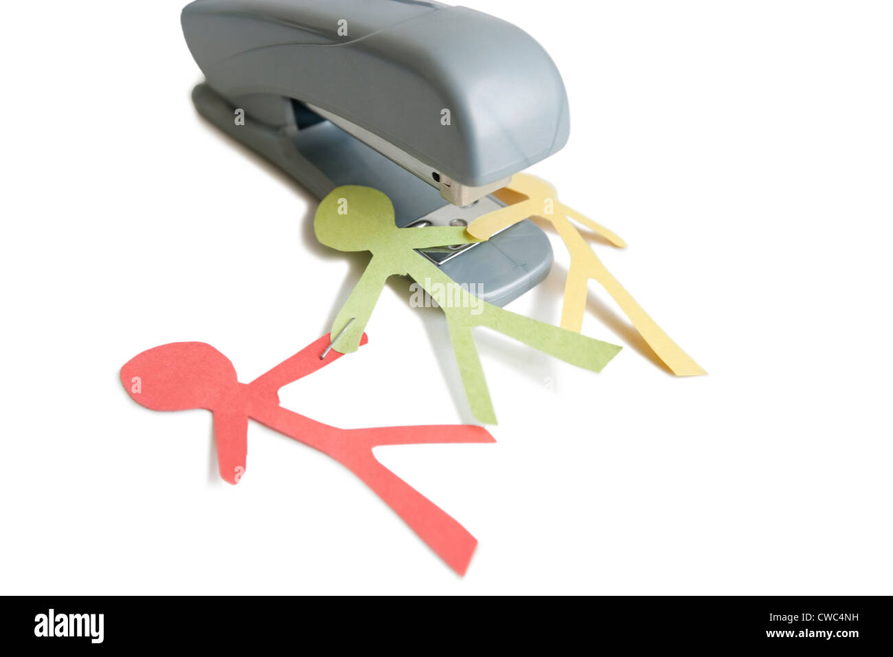 Close-up of paper cut figures being stapled together over white ...