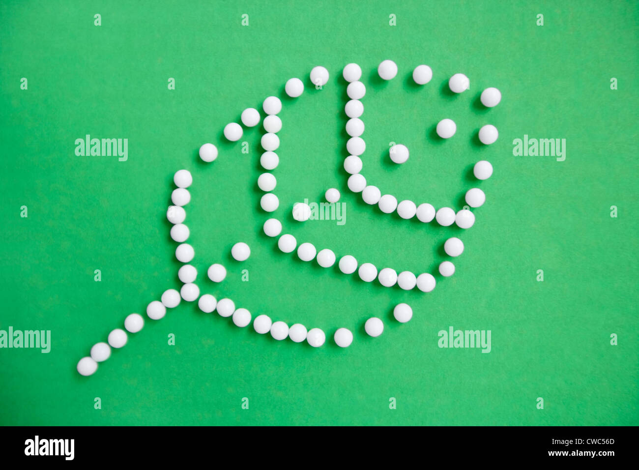 Close-up of push pins forming leaf over green background depicting ...