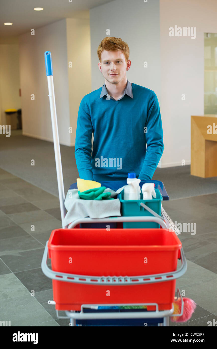 Male cleaner pushing trolley with cleaning equipment Stock Photo - Alamy