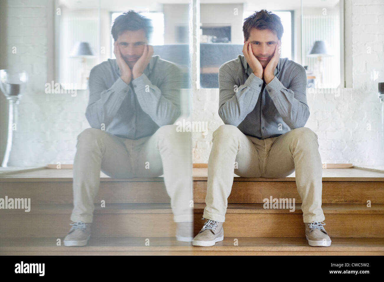Man with his reflection on mirror looking serious Stock Photo - Alamy