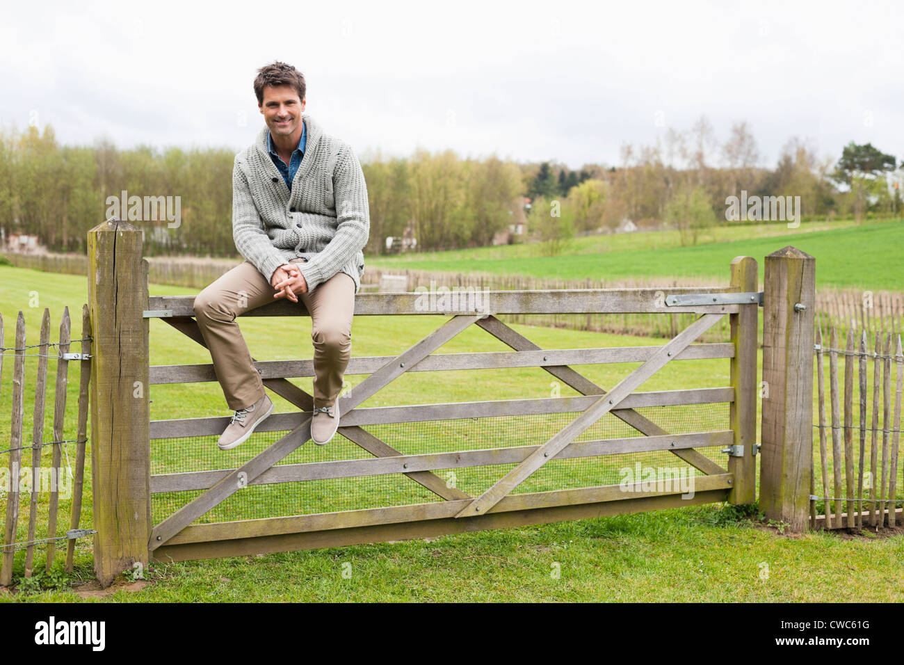 Man sitting on the gate of a cottage Stock Photo - Alamy