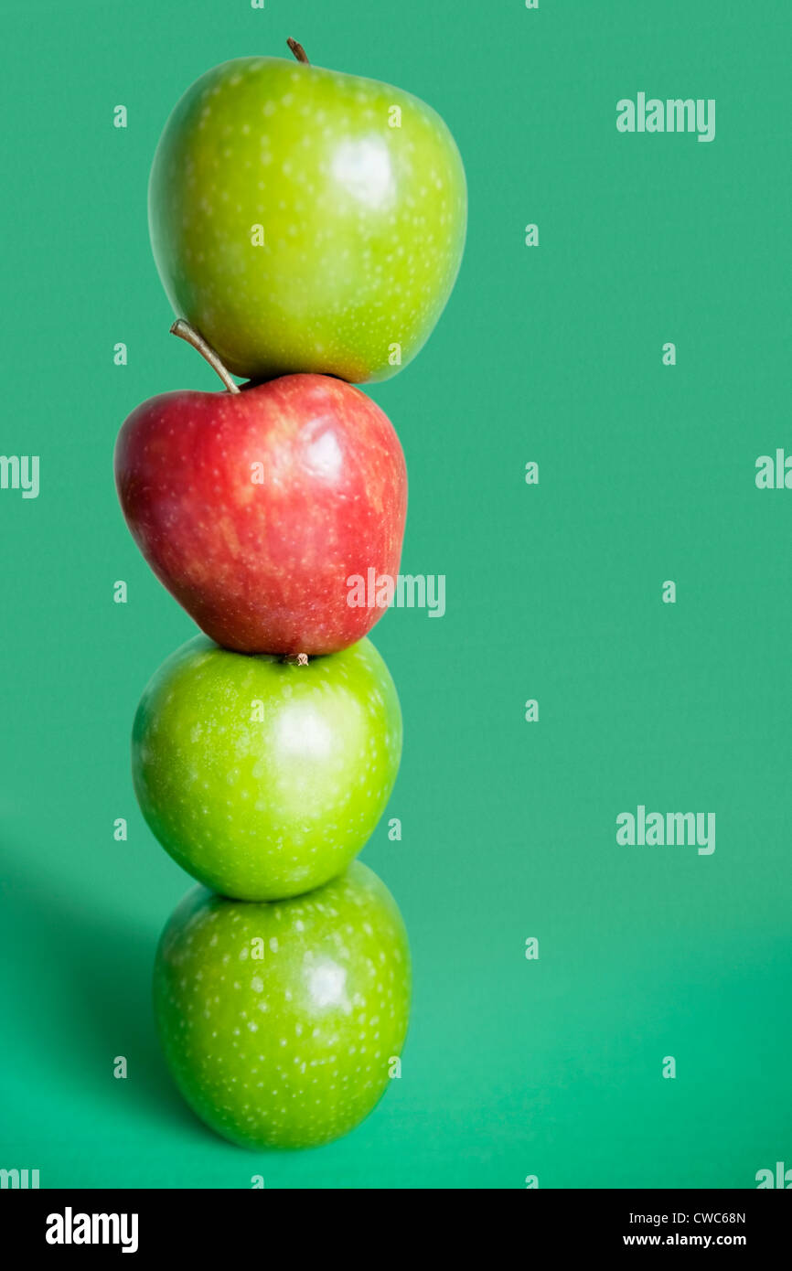 Red and green apples balancing over colored background Stock Photo - Alamy