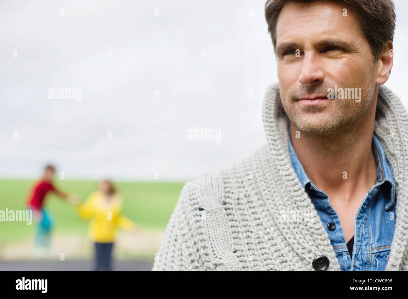 Close-up of a man thinking with his son and wife in the background ...