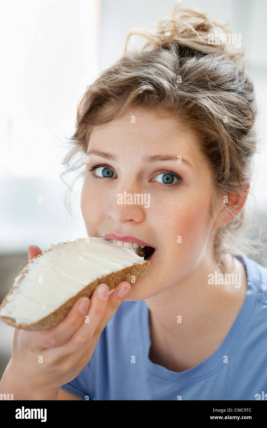 Portrait of a woman eating toast with cream spread on it Stock Photo ...