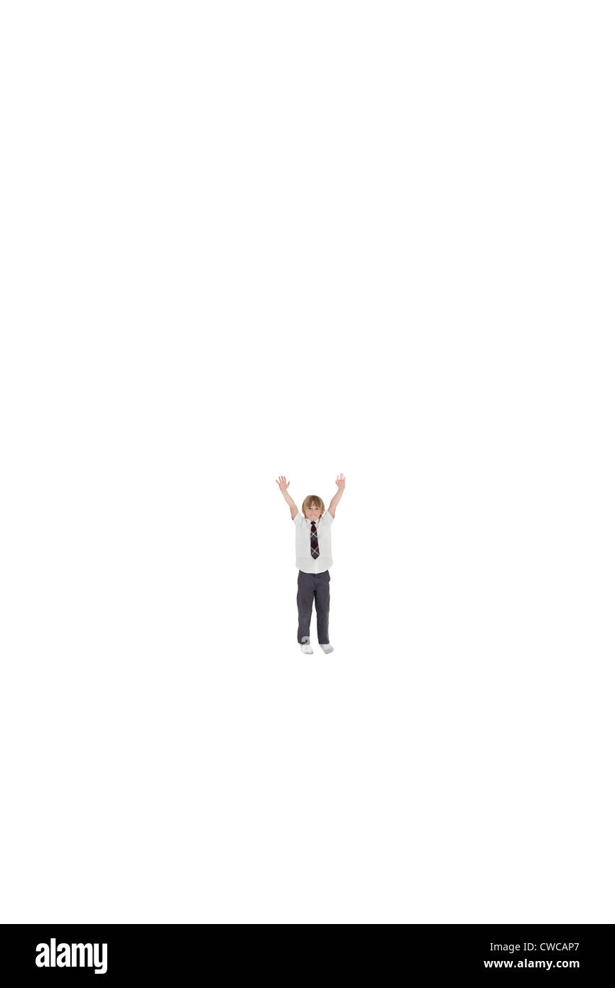 Elementary boy standing at distance with arms raised over white ...