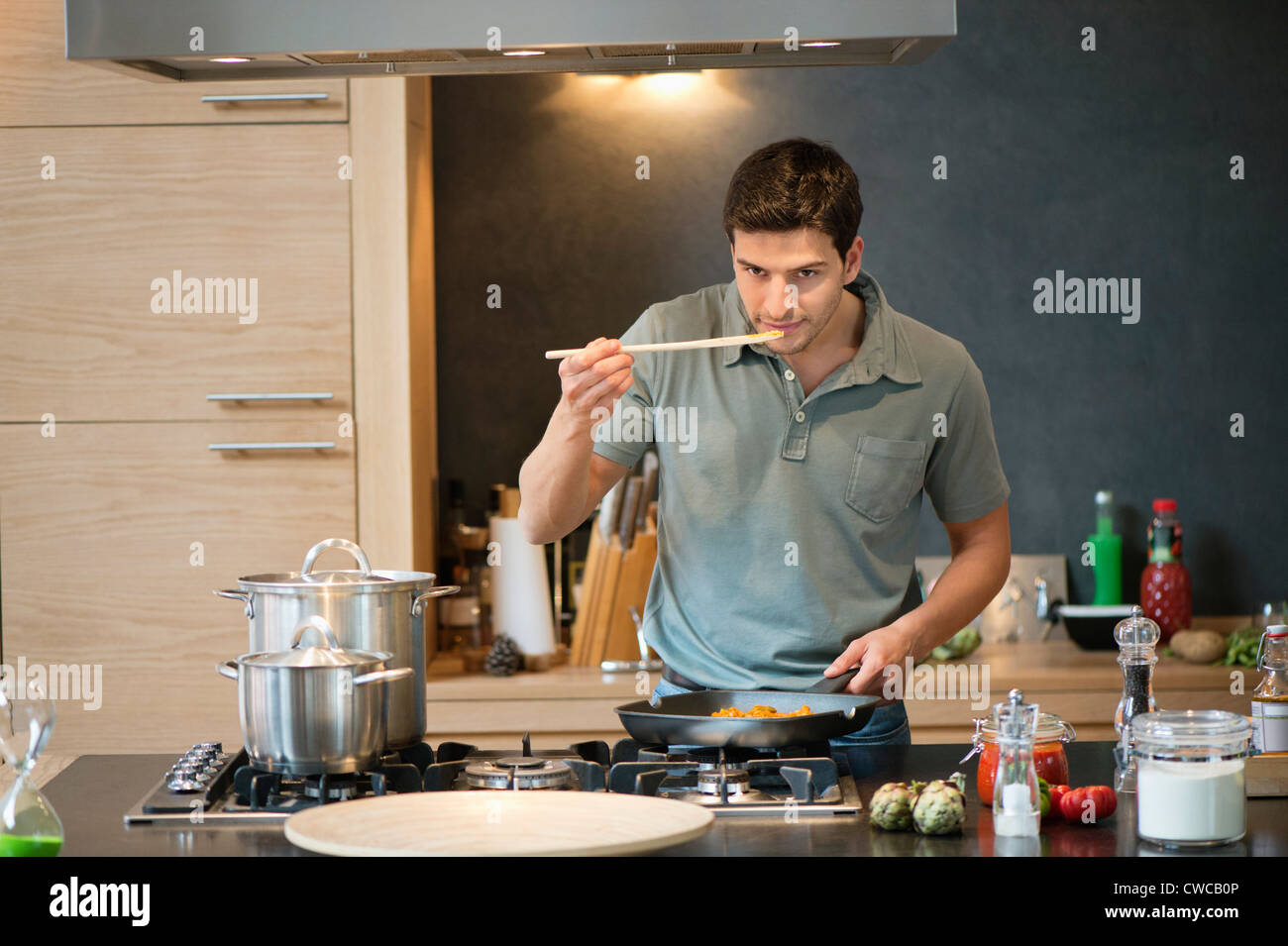 Man tasting food in the kitchen Stock Photo - Alamy