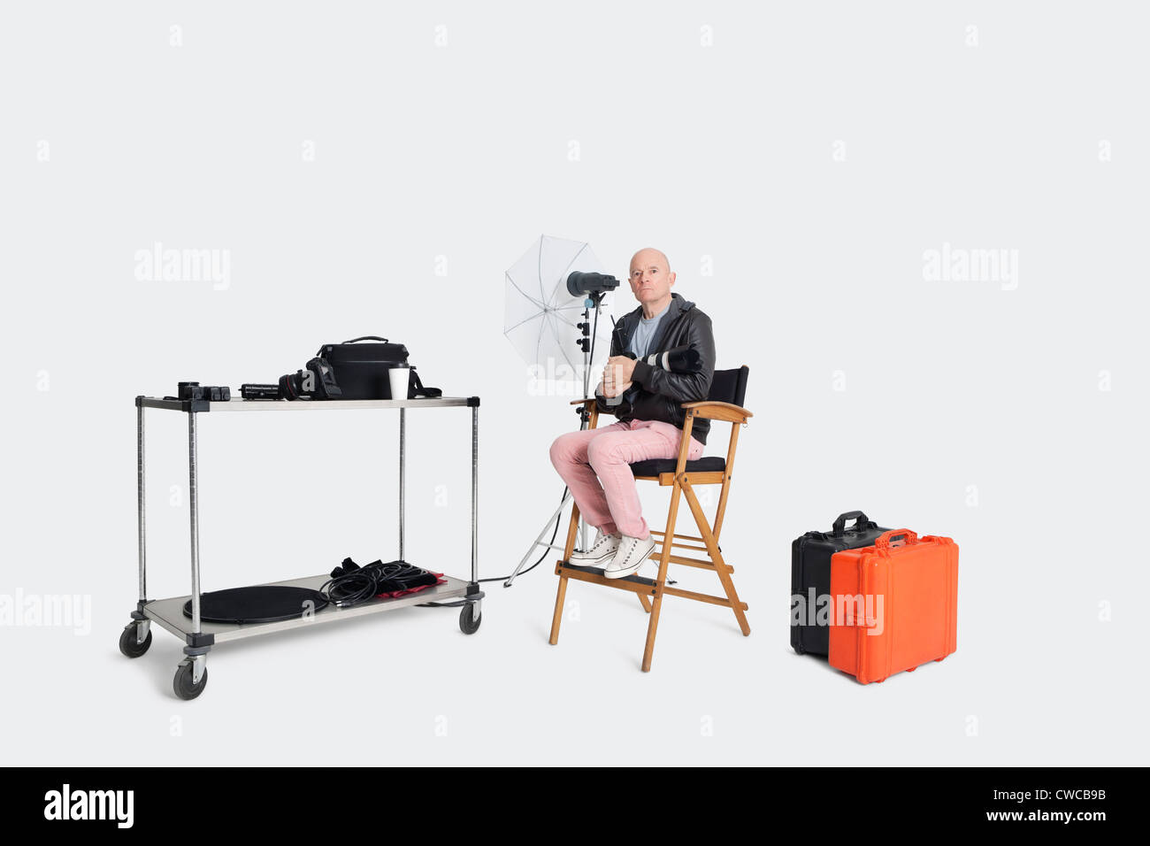 Photographer sitting on director's chair with equipments in studio ...