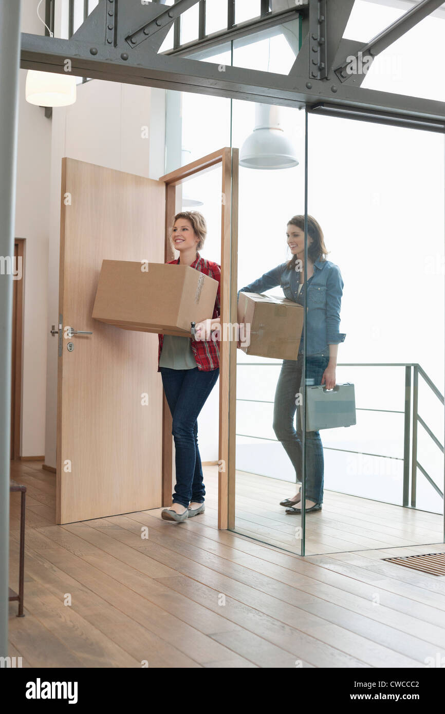 Female friends carrying cardboard boxes at home Stock Photo - Alamy