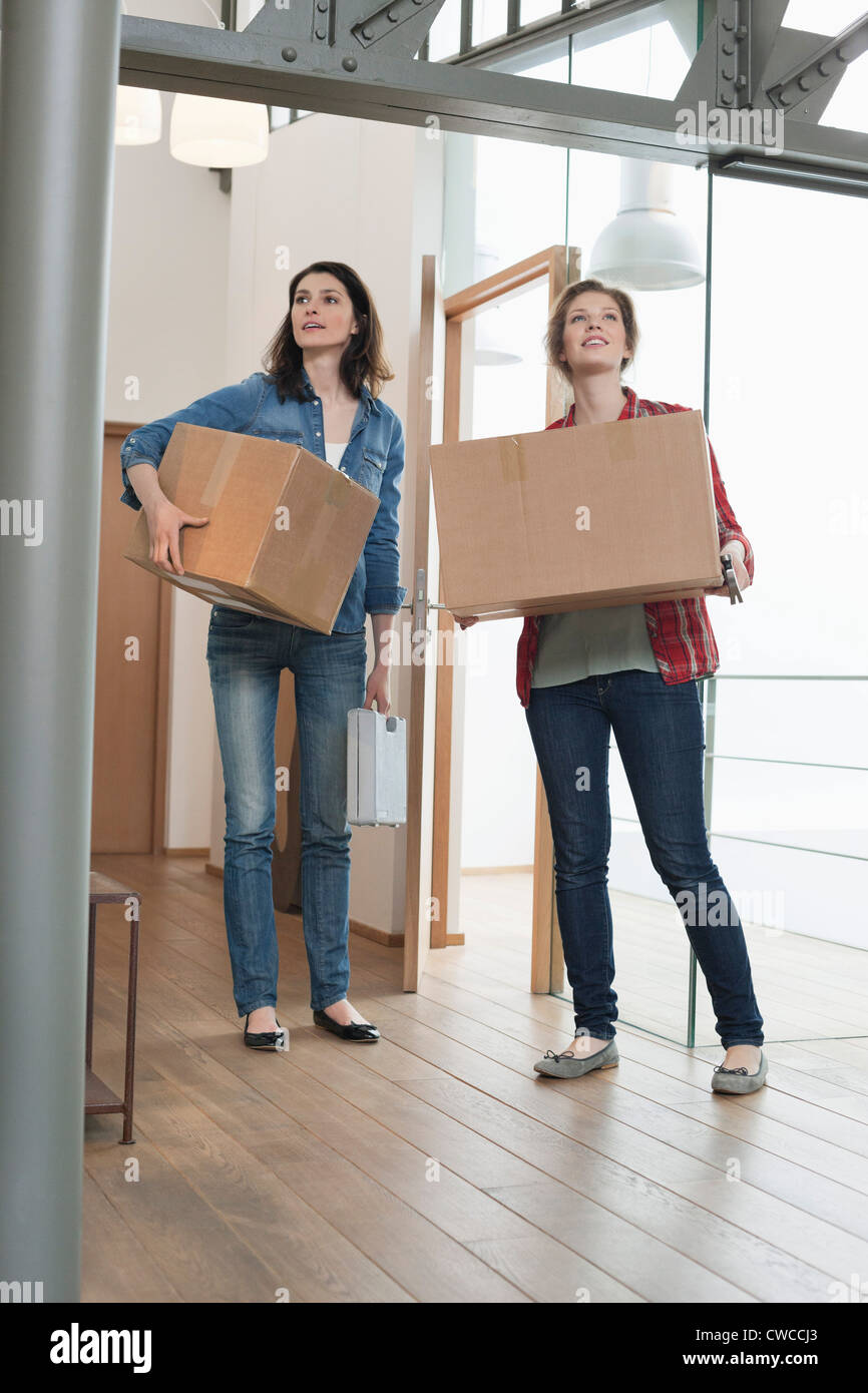 Female friends carrying cardboard boxes at home Stock Photo - Alamy
