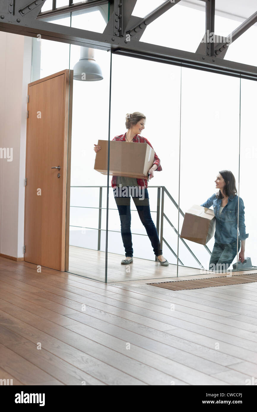 Two female friends carrying cardboard boxes at home Stock Photo - Alamy