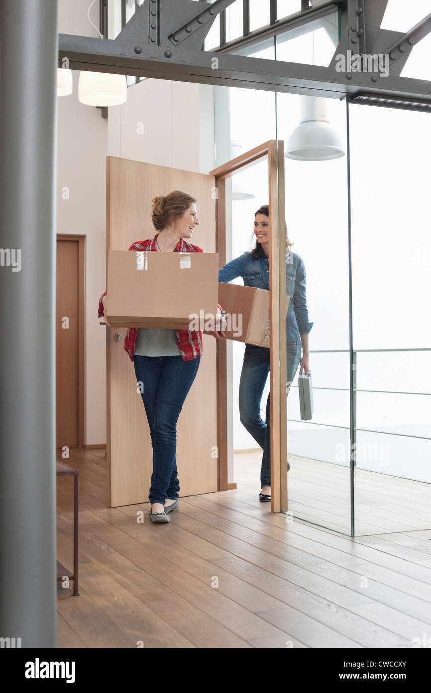 Female friends carrying cardboard boxes at home Stock Photo - Alamy